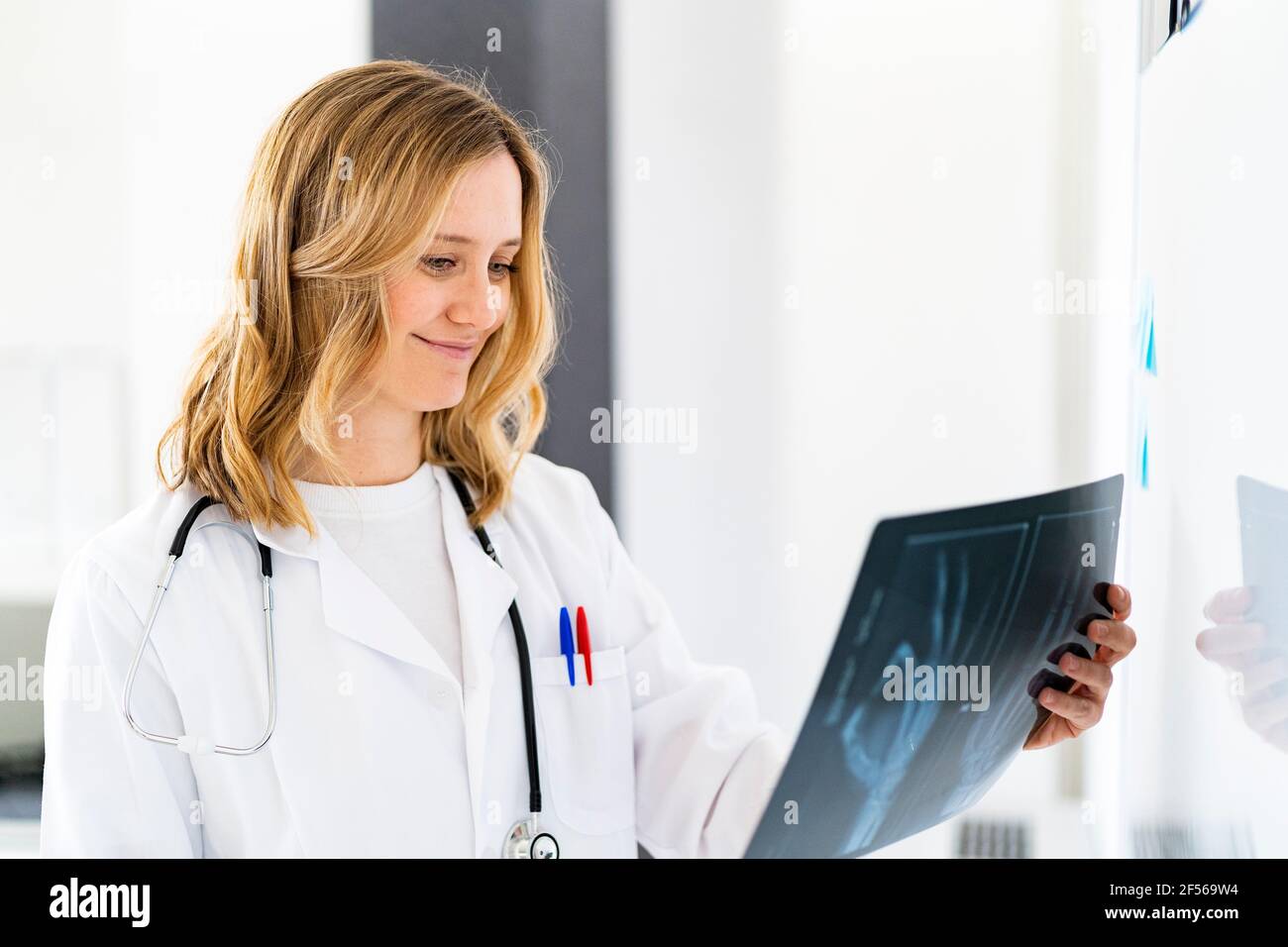 Smiling female doctor holding X-ray at medical clinic Stock Photo - Alamy