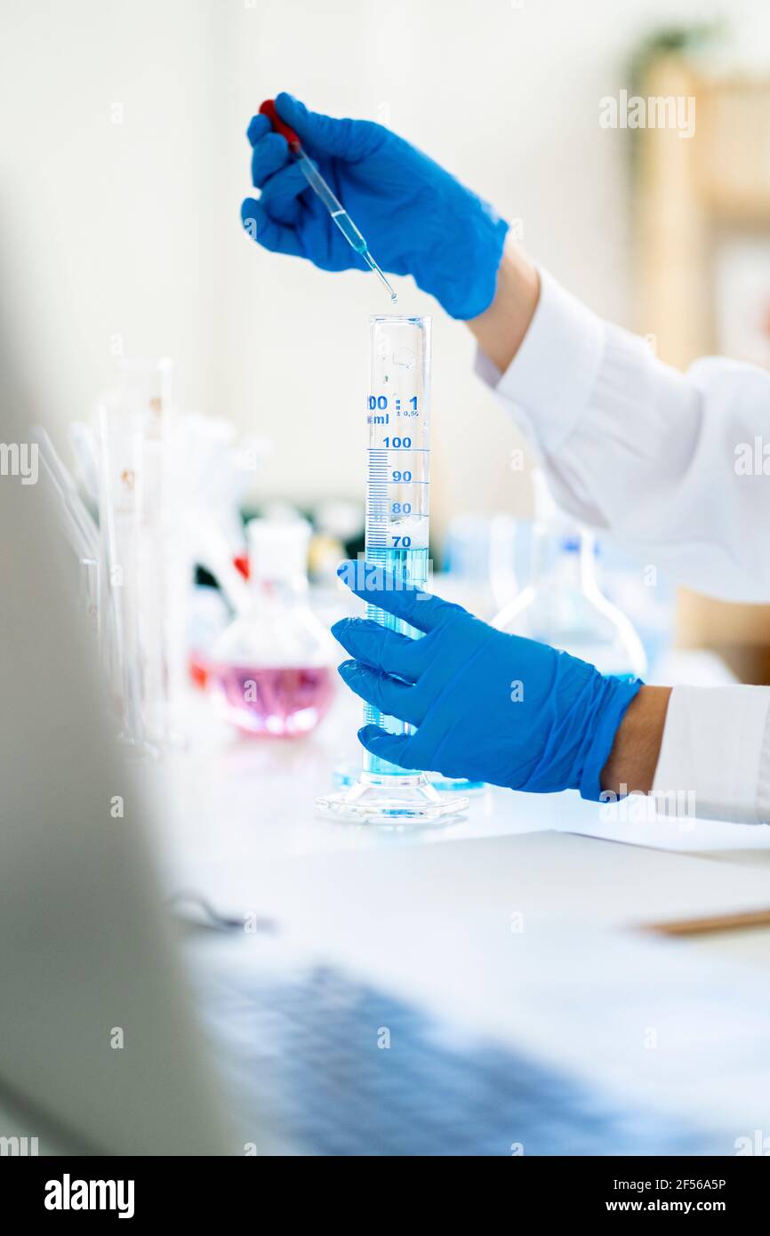Female doctor's hand mixing solution in test tube through pipette at ...