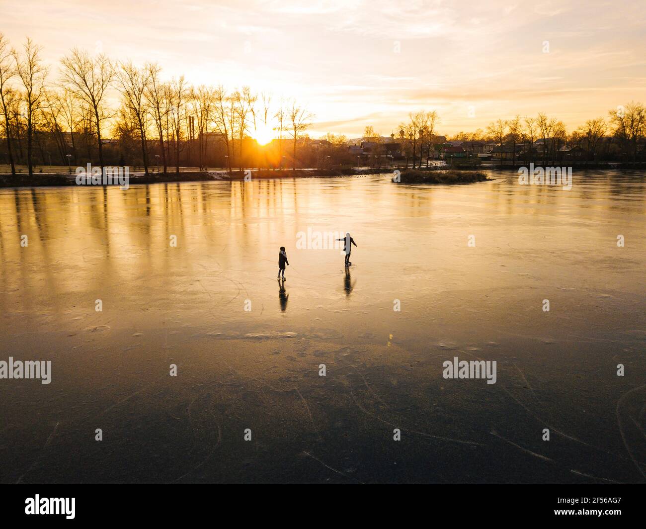 Friends skating on frozen pond during sunset Stock Photo - Alamy