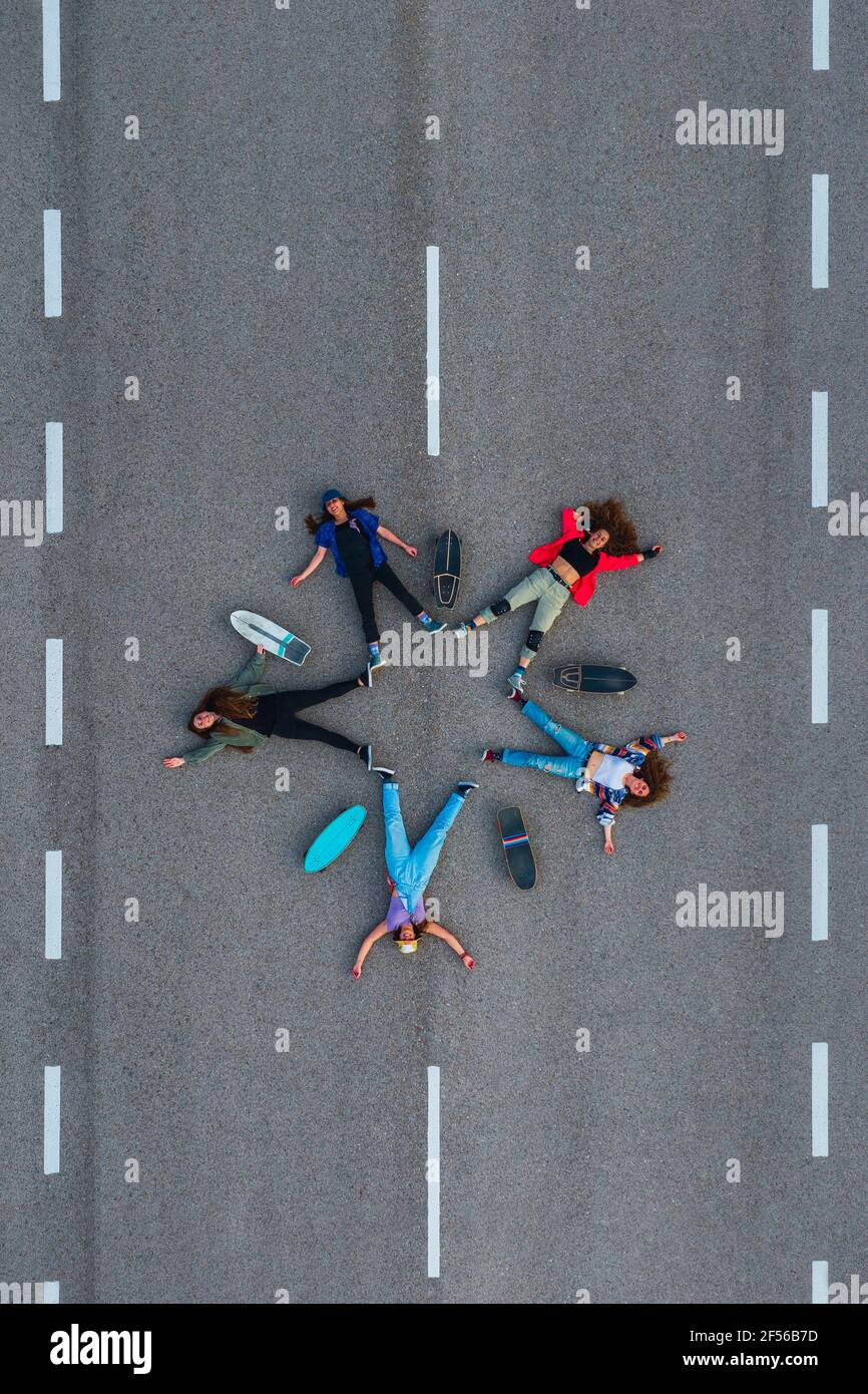 Female friends with arms outstretched lying down on road Stock Photo ...