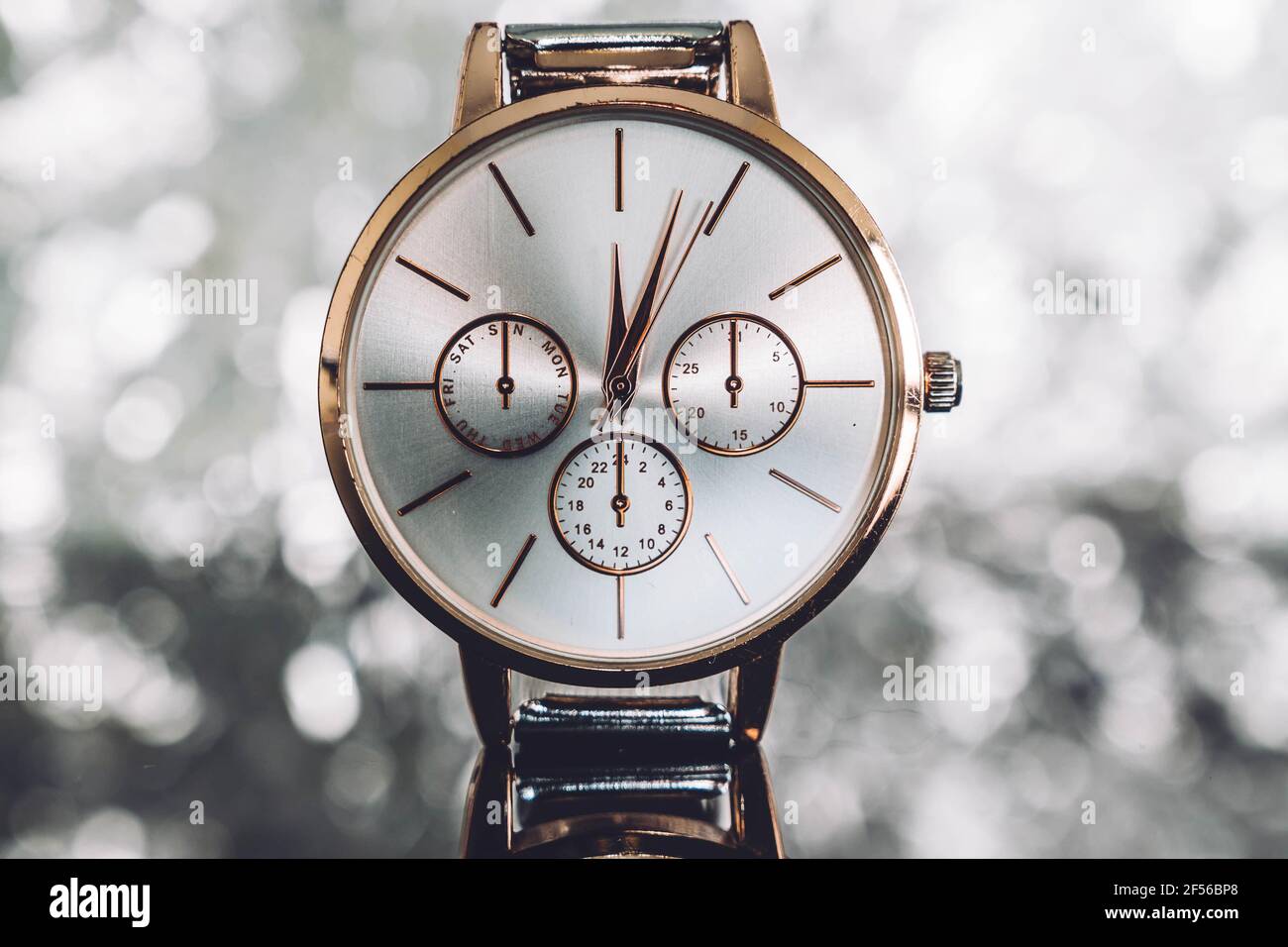 Shiny metal gold silver womans wrist watch on mirror surface on black ...