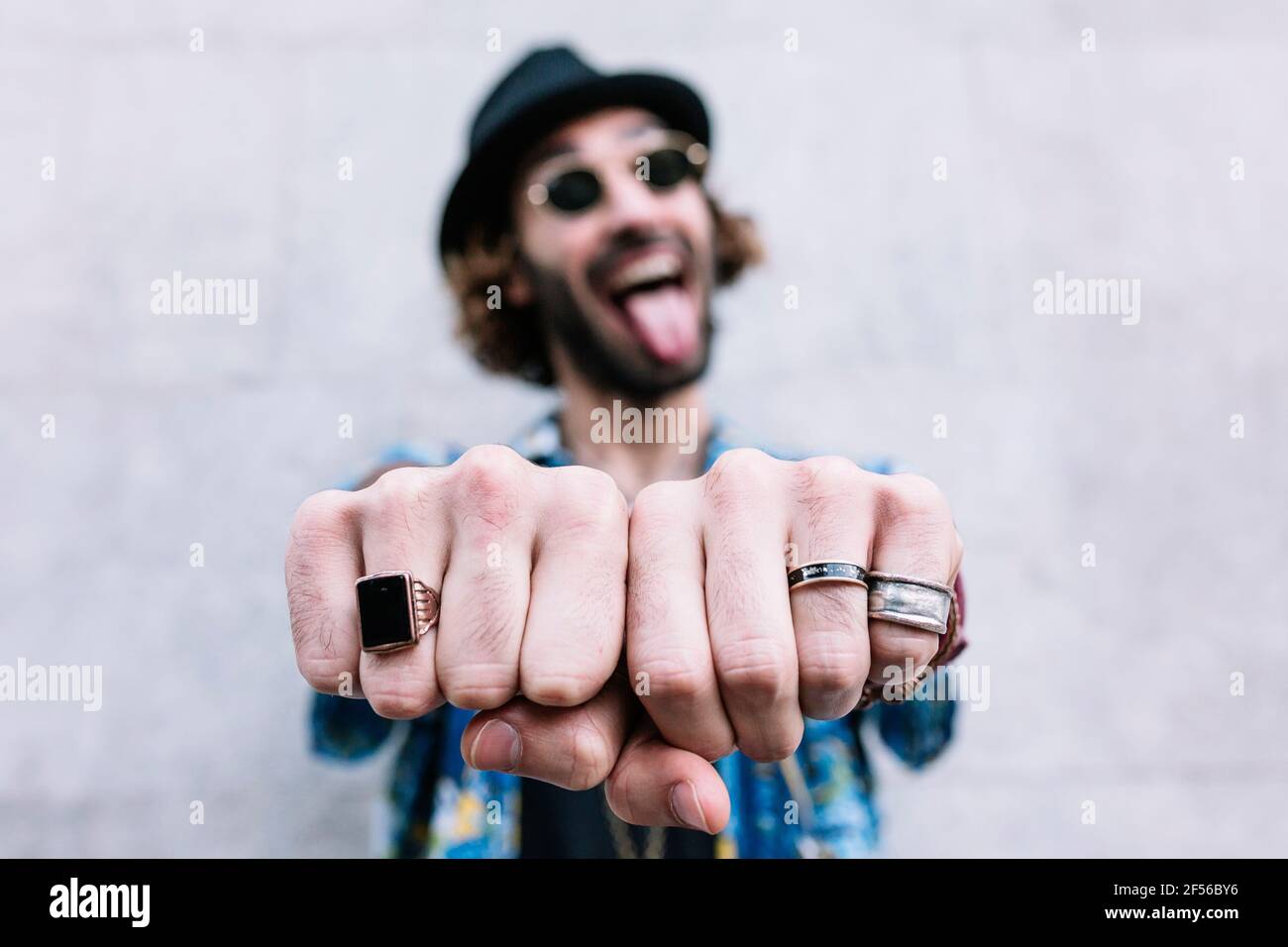 Hipster man showing knuckles while standing in front of wall Stock ...