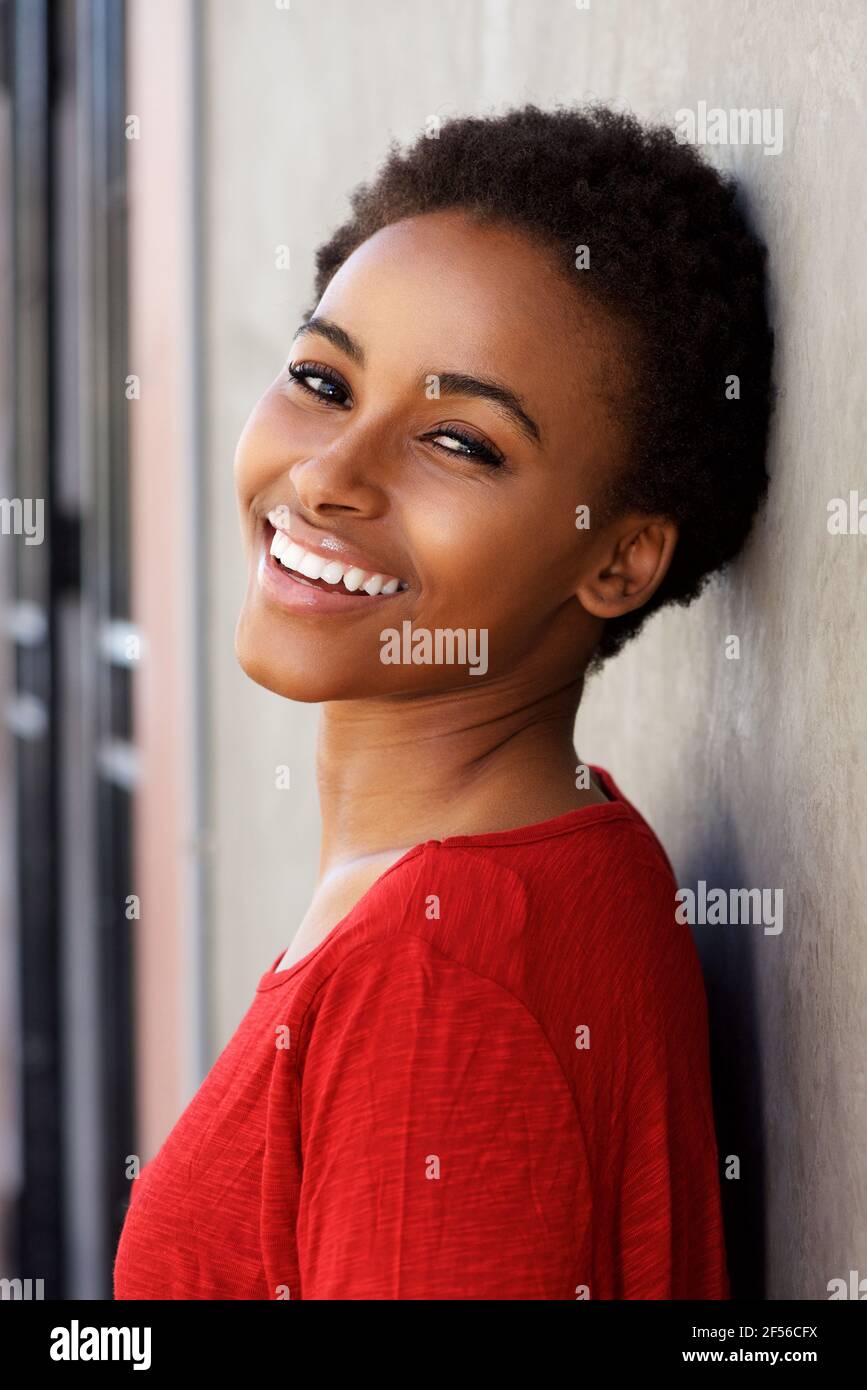 Side portrait of smiling young black woman leaning against wall Stock ...