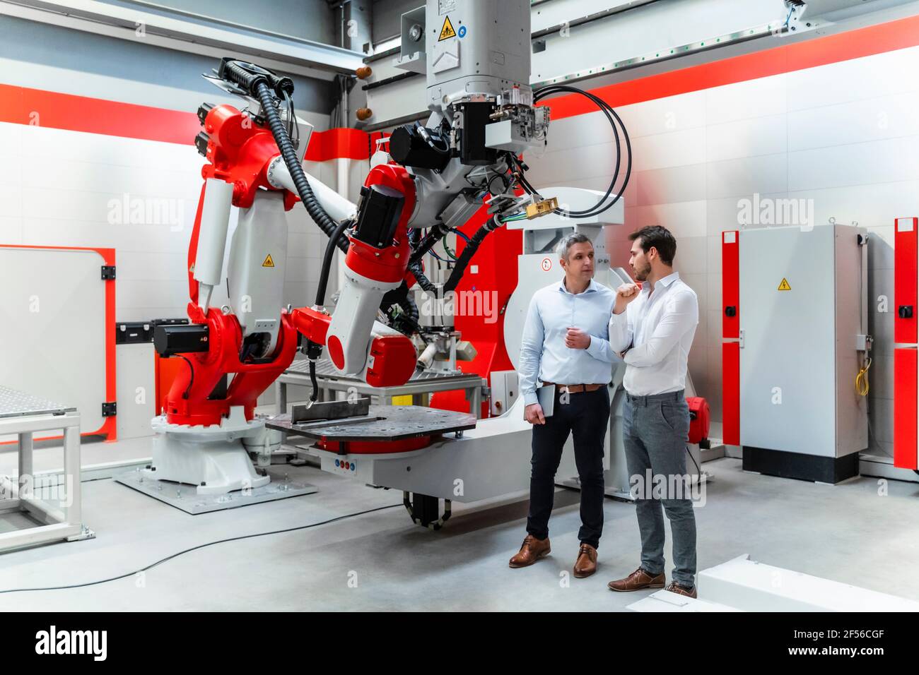 Male automation engineers discussing by machinery in factory Stock ...