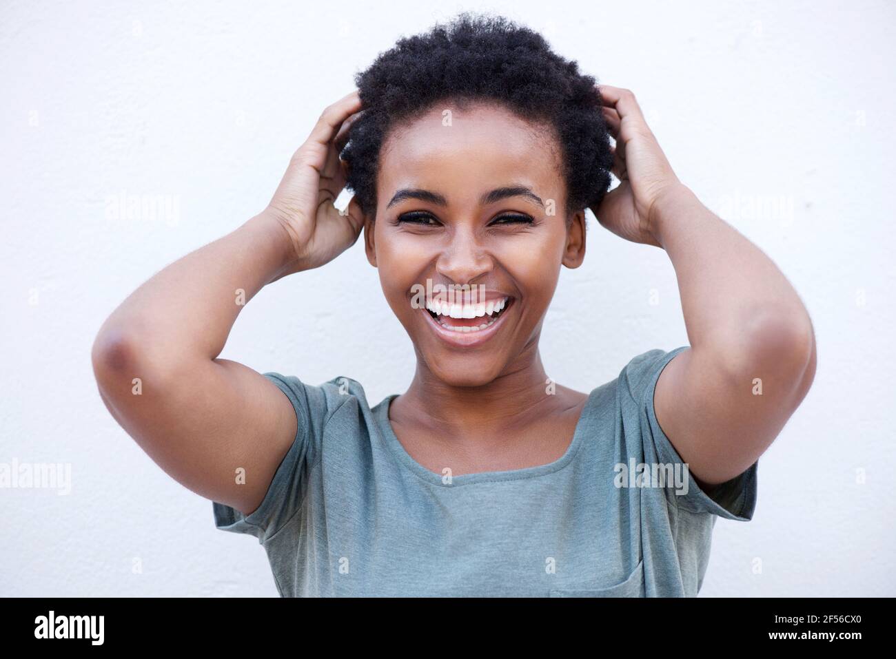 Portrait of attractive young black woman laughing with hands in hair ...