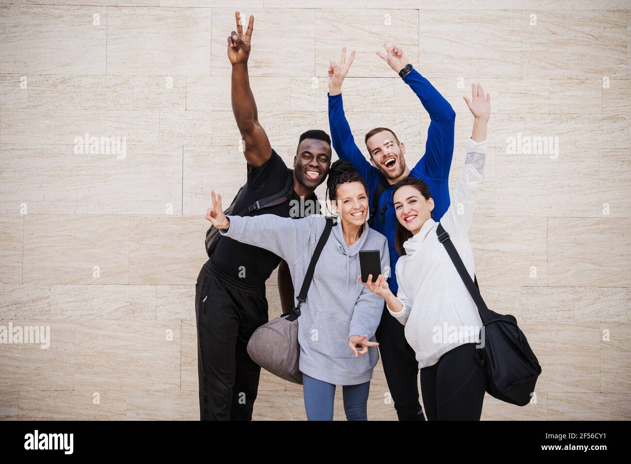 Happy sports people gesturing peace sign while standing in front of ...
