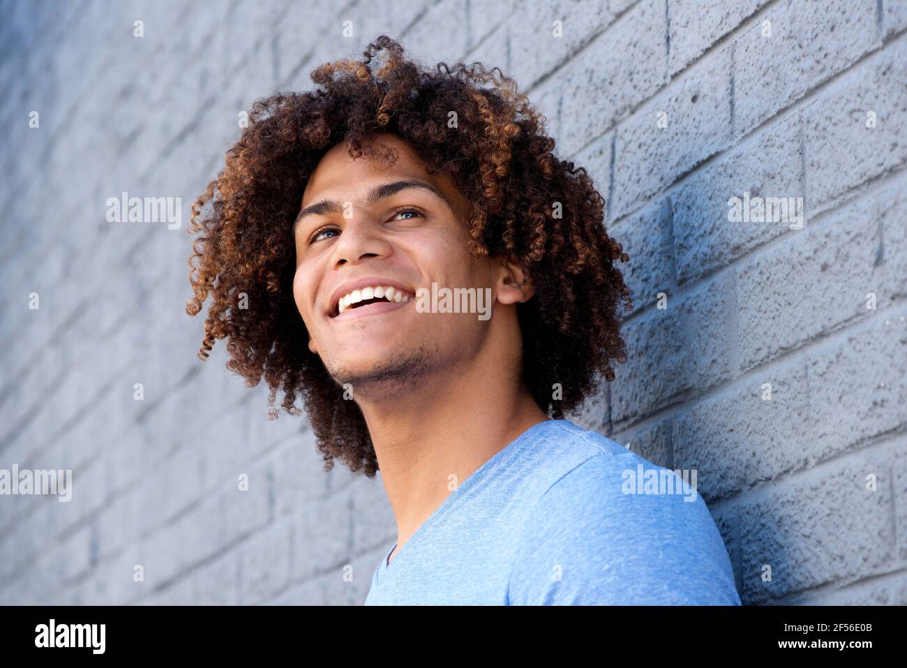 Close up side portrait of cool young man with curly hair smiling ...