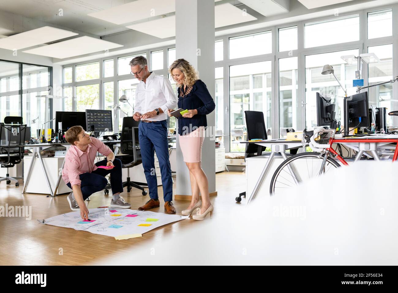 Male business professional explaining project to colleagues in open ...