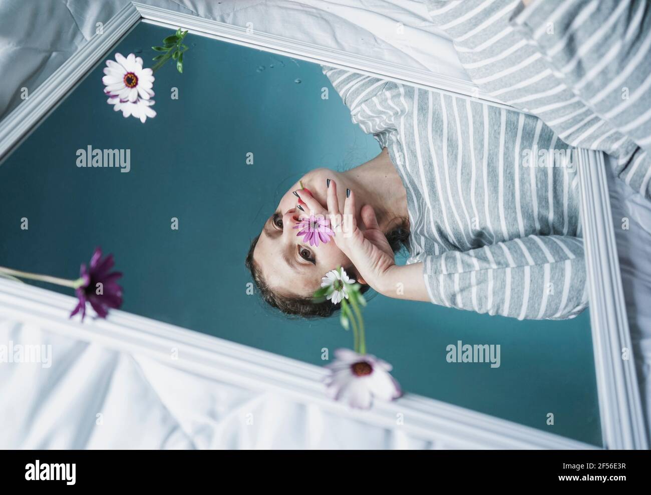 Young woman reflecting in mirror lying on bed Stock Photo - Alamy