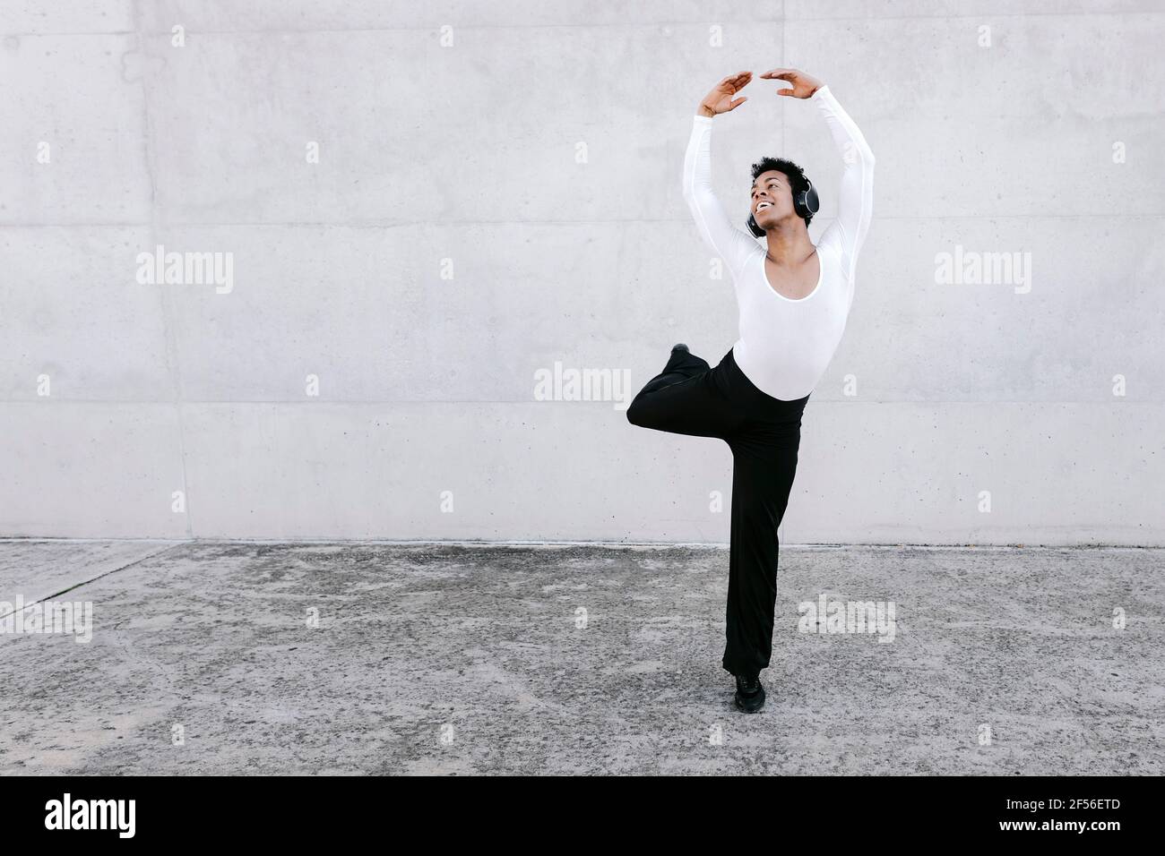 Male dancer balancing on one leg while dancing in white wall Stock ...