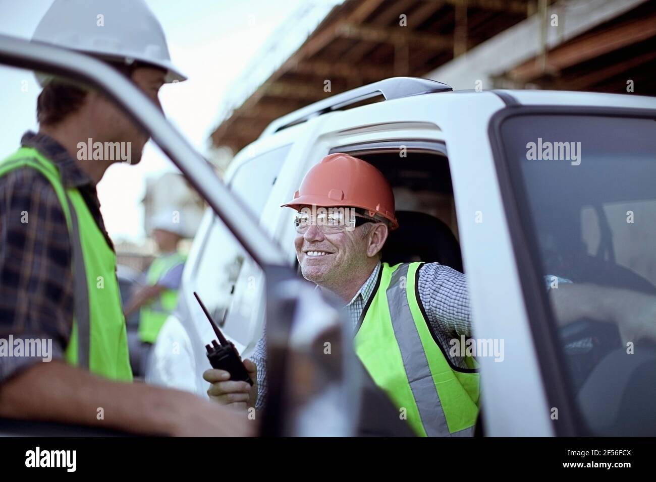 Two male construction workers chatting by car Stock Photo - Alamy