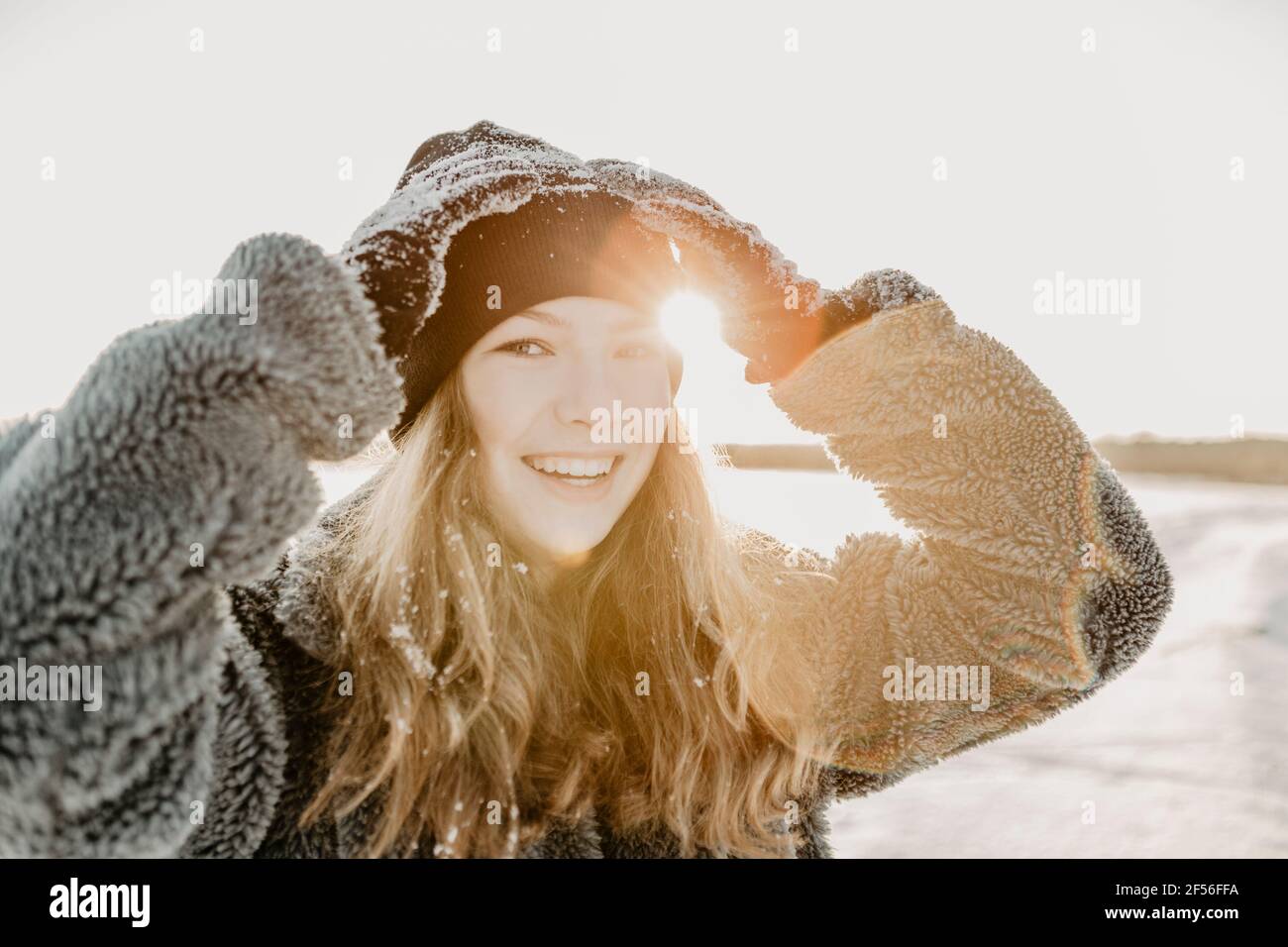 Portrait of beautiful teenage girl adjusting knit hat while smiling at ...