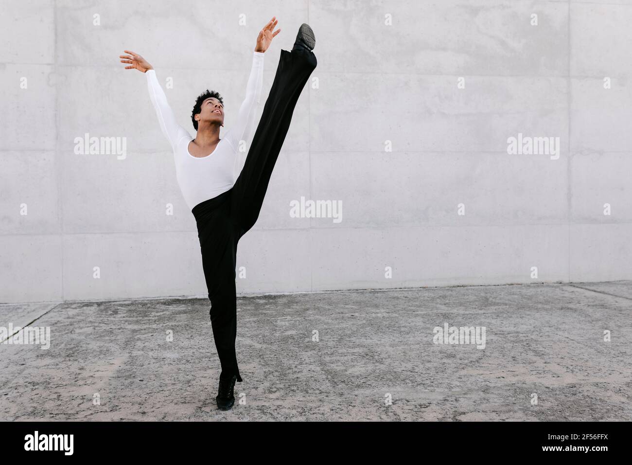 Flexible male dancer looking up while stretching leg against wall Stock ...