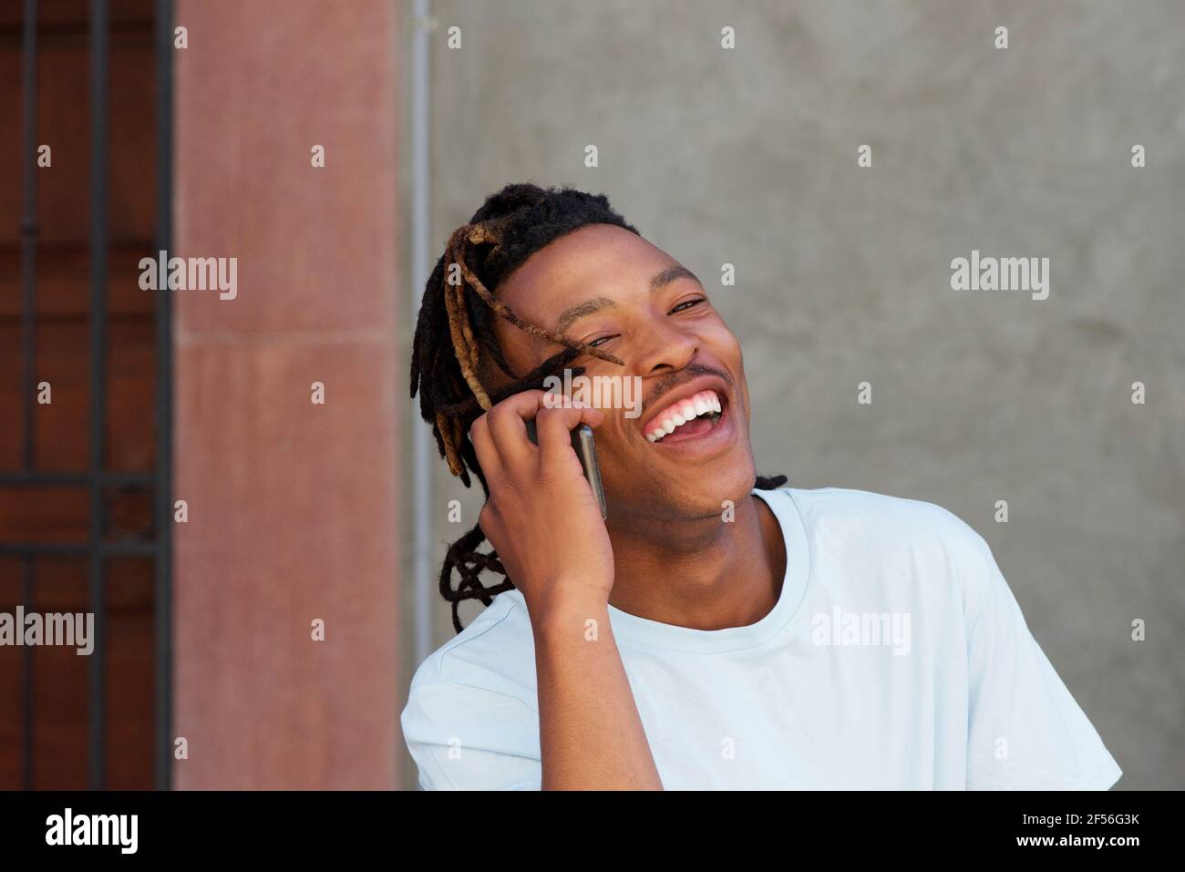 Portrait of cool african guy with dreadlocks laughing and talking on ...