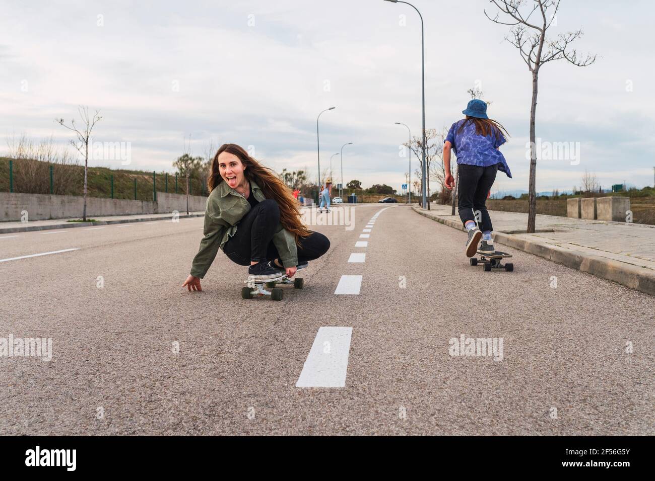 Female friends skating on road Stock Photo - Alamy