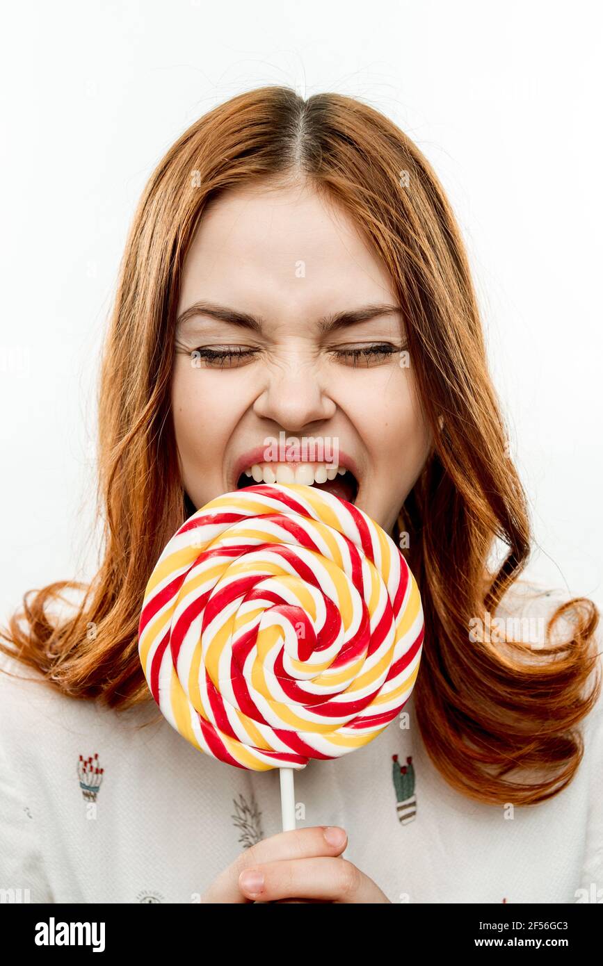 emotional woman with round multicolored lollipop near face enjoyment ...