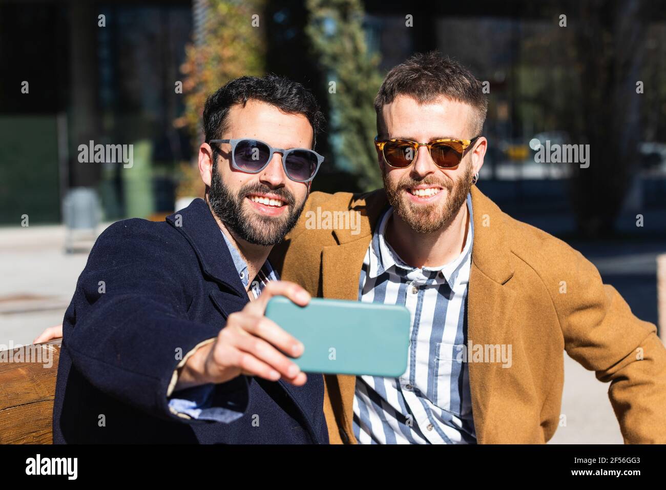 Smiling business partners taking selfie through mobile phone while ...