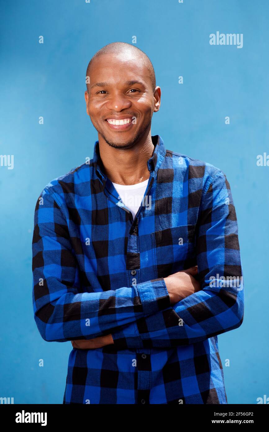 Portrait of handsome young man standing with his arms crossed against ...