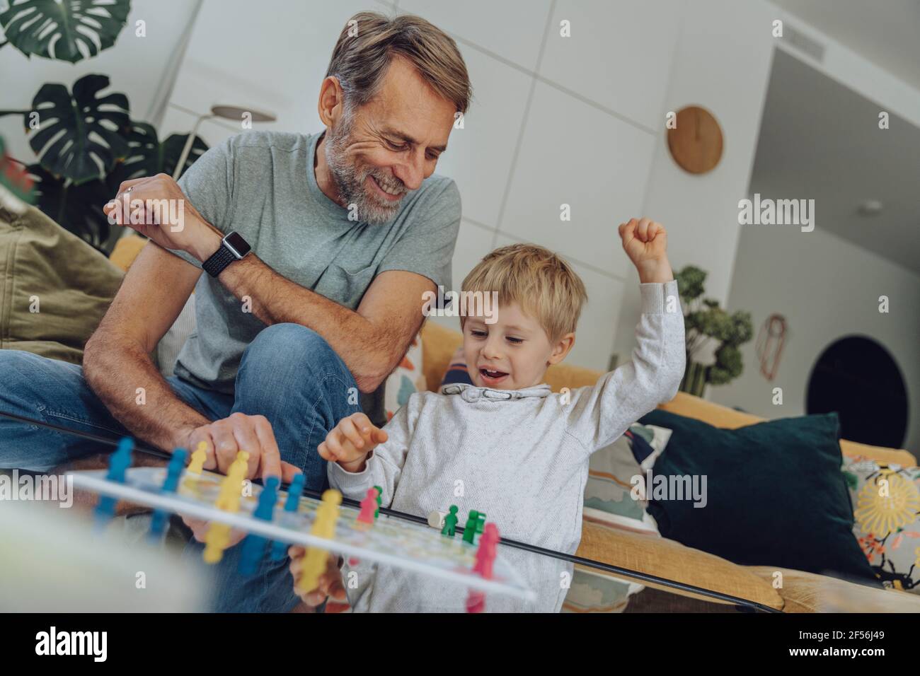 Happy boy playing board game with father in living room Stock Photo - Alamy