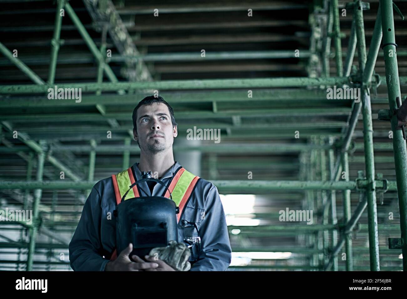 Thoughtful male construction worker looking away at construction site ...