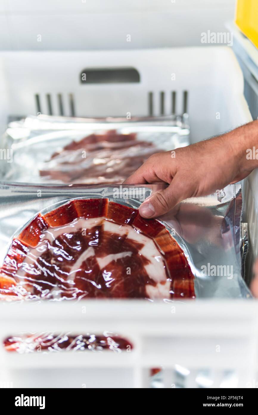 Male butcher keeping packet of ham meat in crate Stock Photo - Alamy