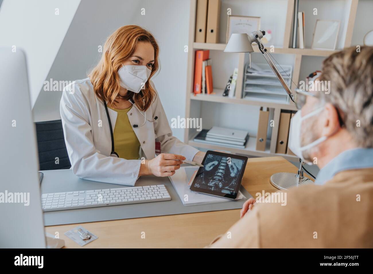 General practitioner explaining over x-ray on digital tablet to patient ...
