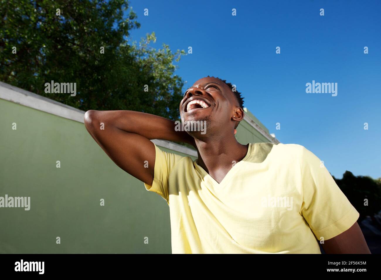 Portrait of laughing young african man walking outside Stock Photo - Alamy