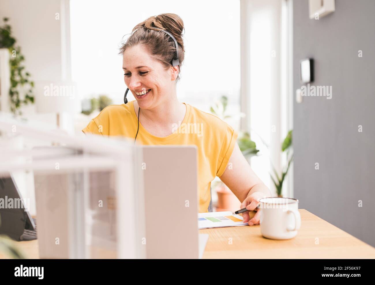 Cheerful female professional wearing headphones while video ...
