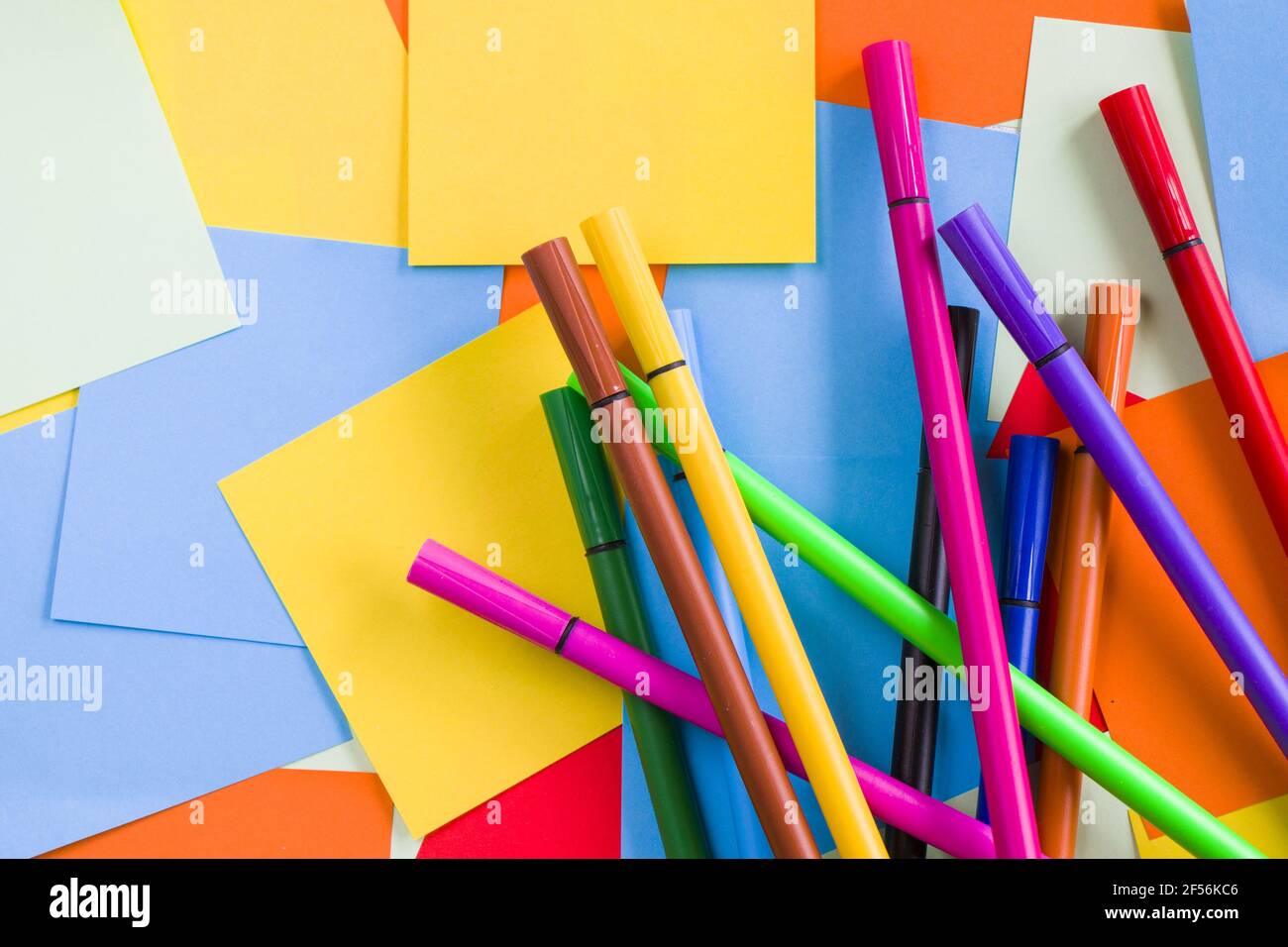 Overhead shot of a set of sketch markers on colorful blank note papers ...