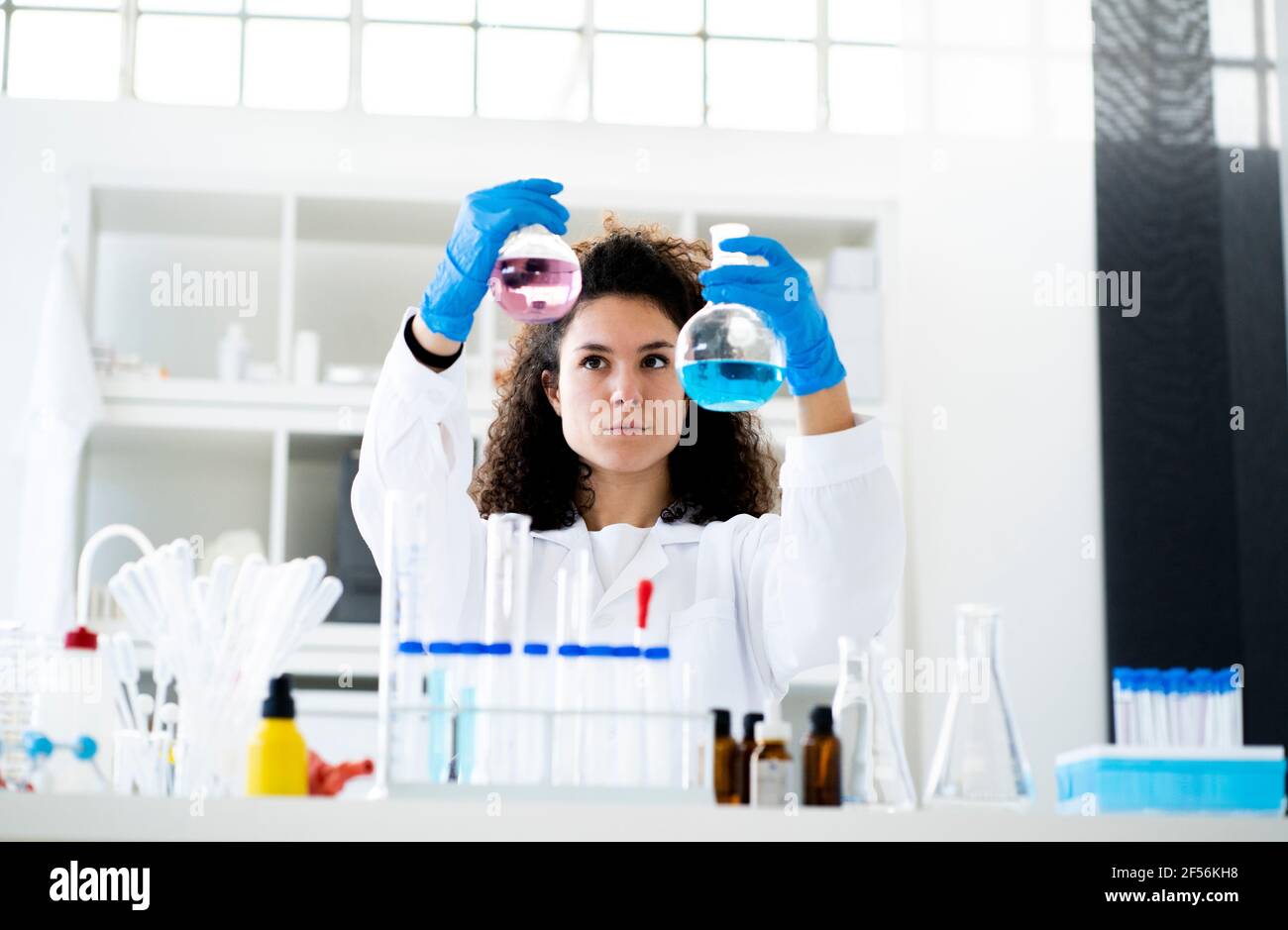 Female scientist checking chemical solution in beaker at laboratory ...
