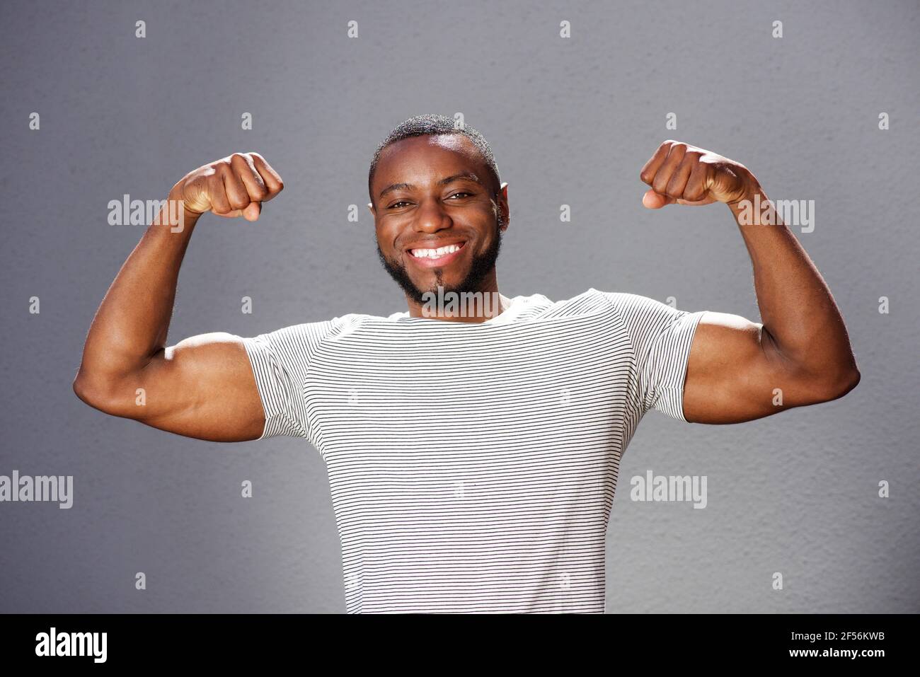 Close up portrait of young smiling man flexing arm muscles Stock Photo ...