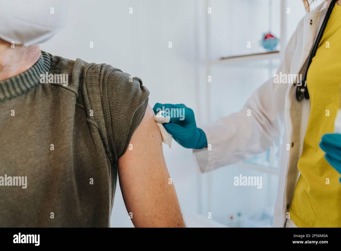 Doctor cleaning patient arm while preparing for vaccination at ...