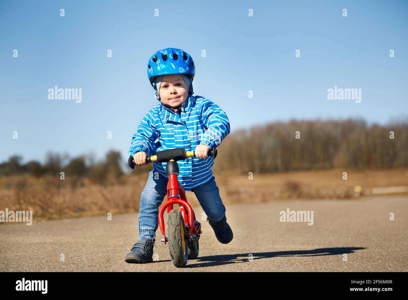 Boy pushing while playing with balance bike on road Stock Photo - Alamy