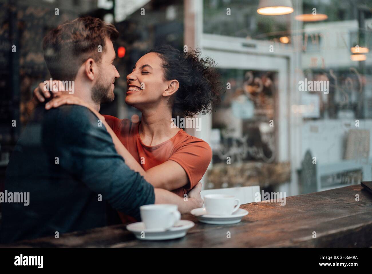 Romantic couple smiling while sitting with arm around on each other at ...