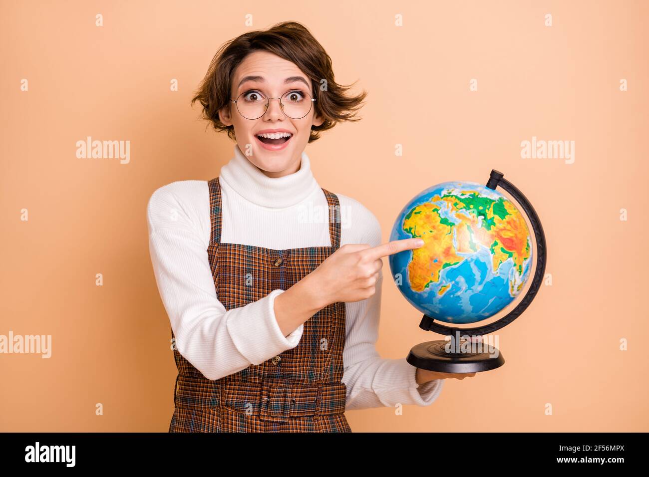 Photo portrait of excited smart female nerd pointing finger at globe in ...