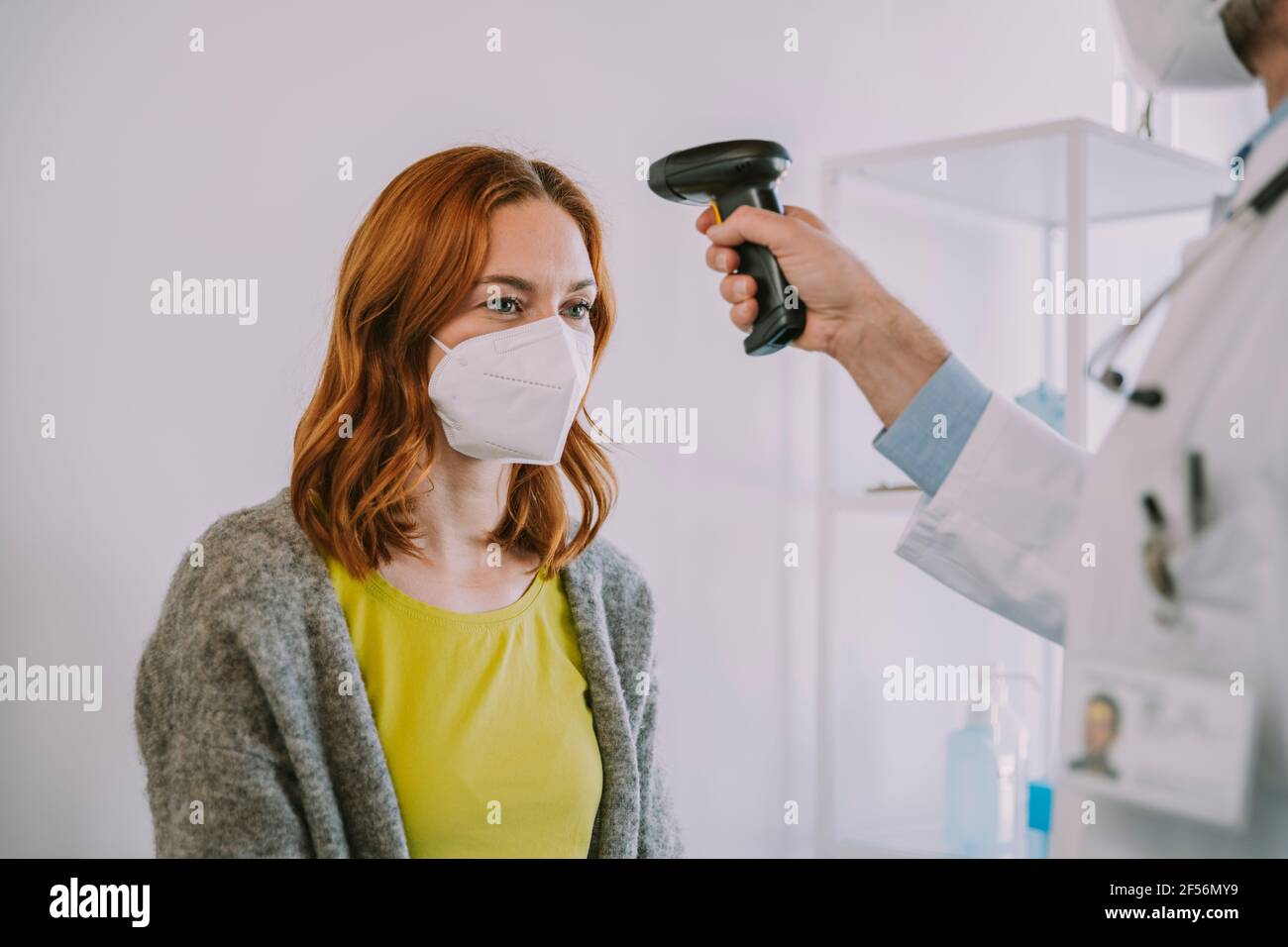 Doctor checking patient temperature through infrared thermometer while ...