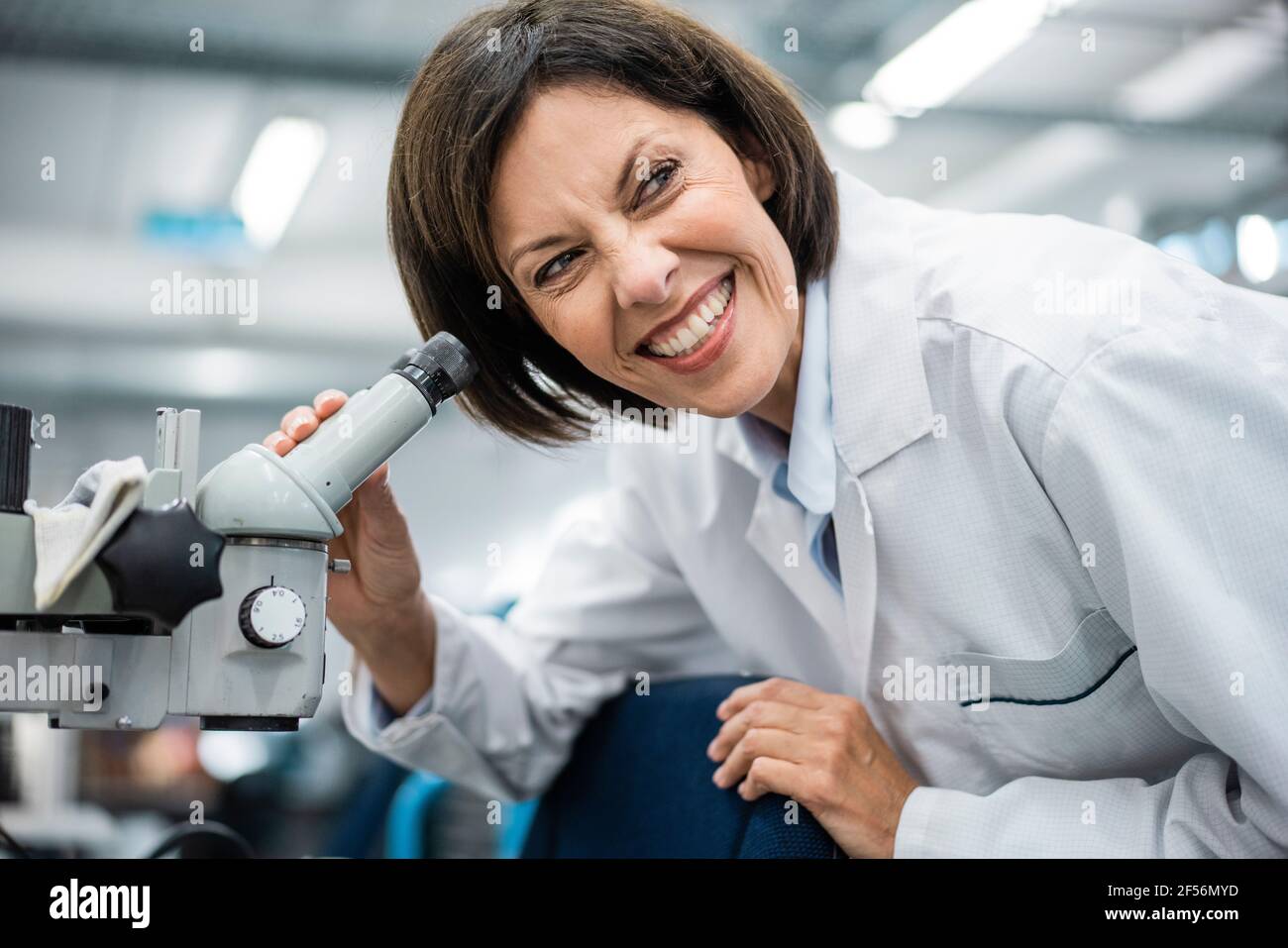 Smiling female scientist holding microscope at laboratory Stock Photo ...