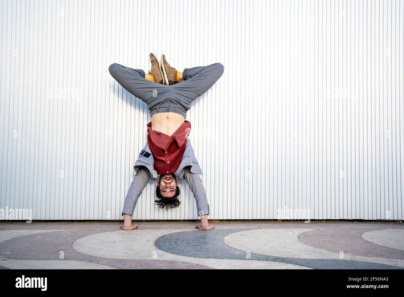 Male business professional doing handstand in front of wall Stock Photo ...