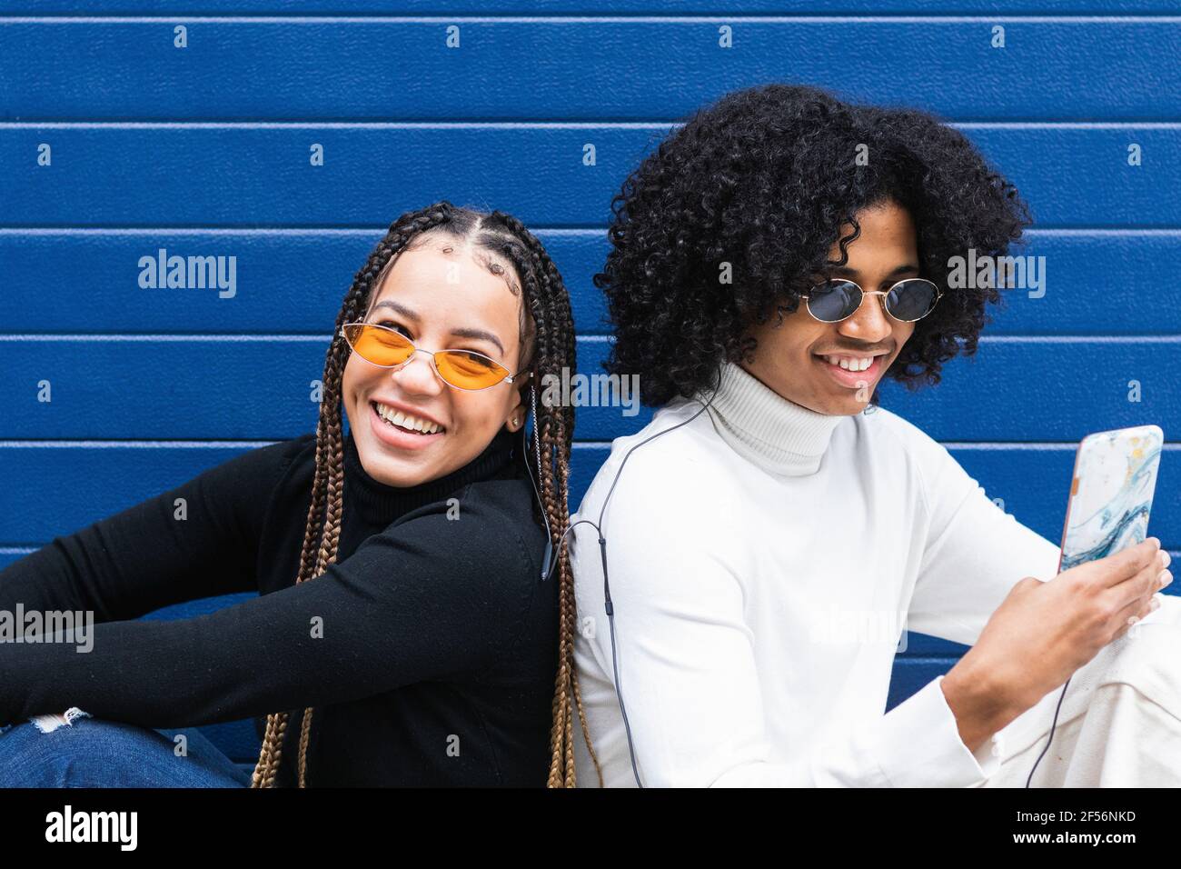Boyfriend sitting back to back while using mobile phone sitting against ...