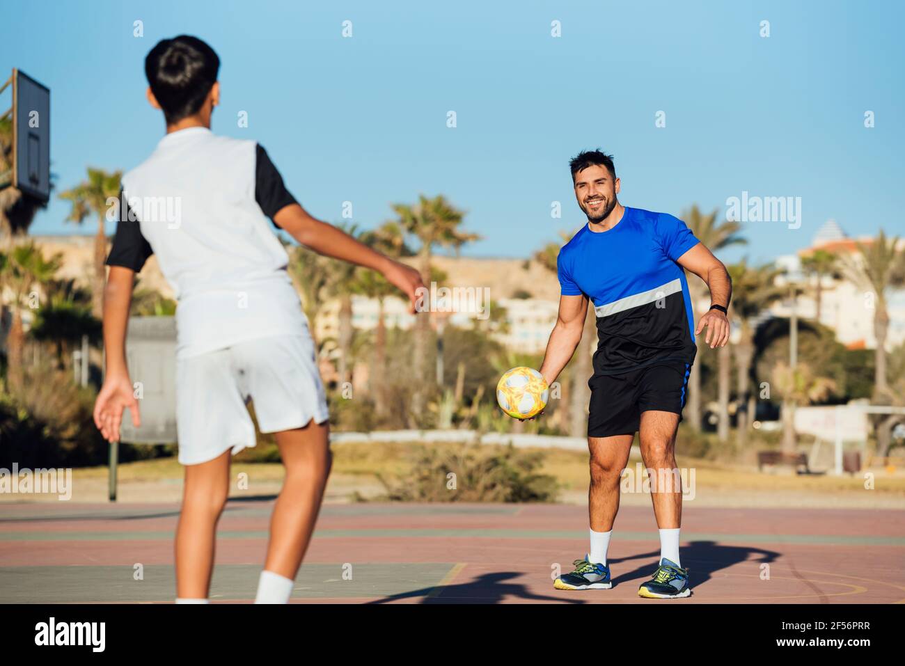 Father throwing ball at son in sports court Stock Photo - Alamy