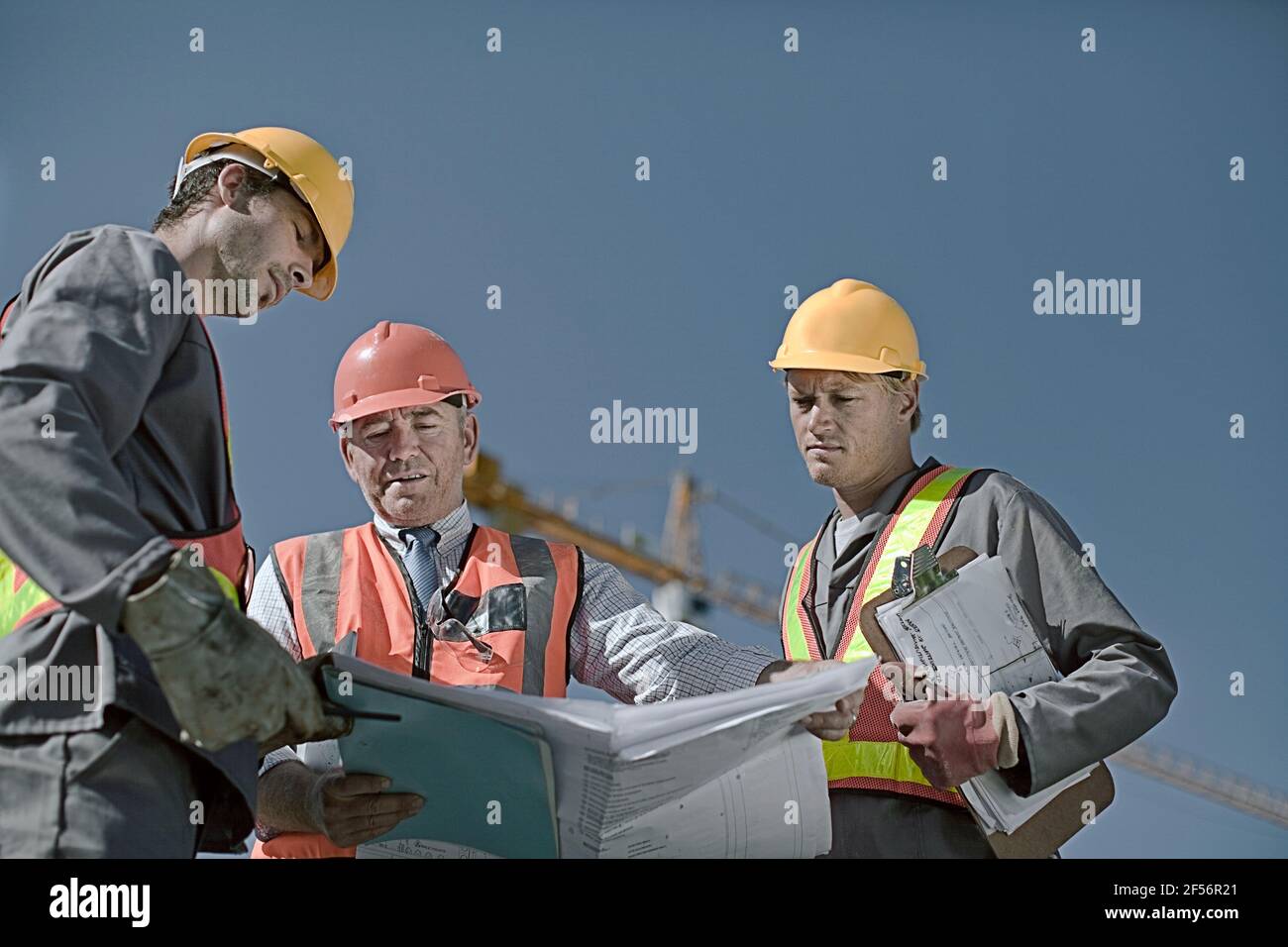 Male construction worker discussing with coworkers at construction site ...