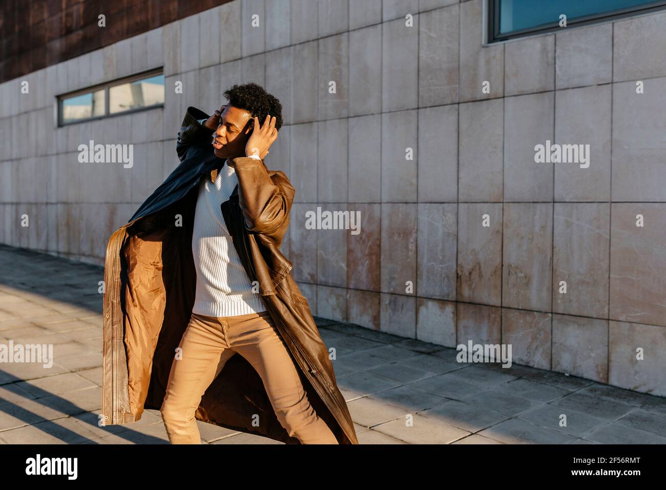 Male dancer enjoying music while dancing against building Stock Photo ...