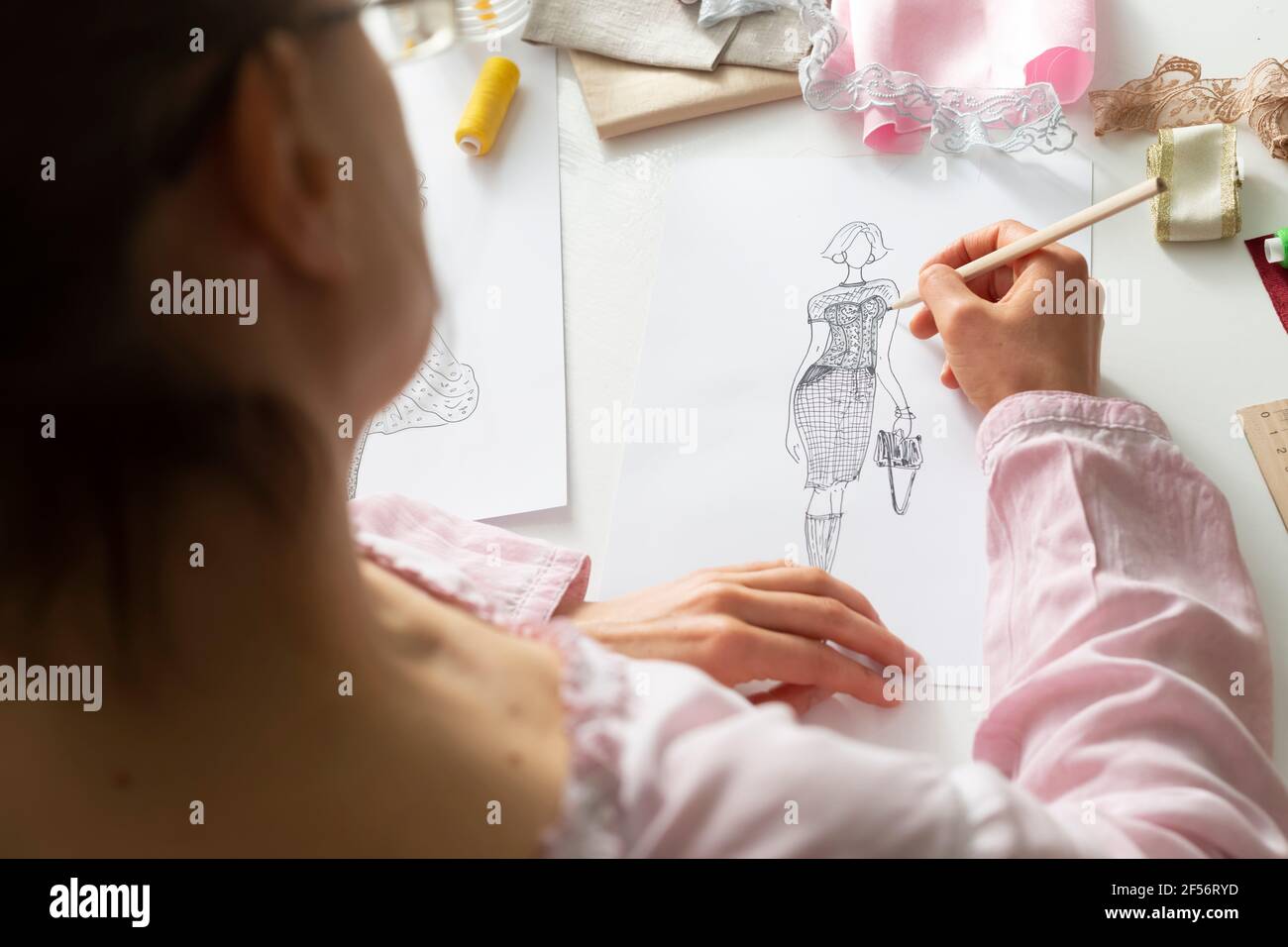 The designer draws sketches of fashionable women's clothing on paper at ...