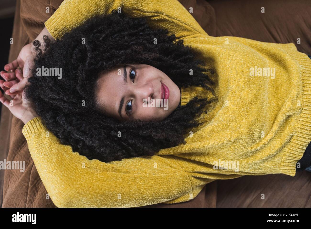 Curly haired woman lying on sofa at home Stock Photo - Alamy