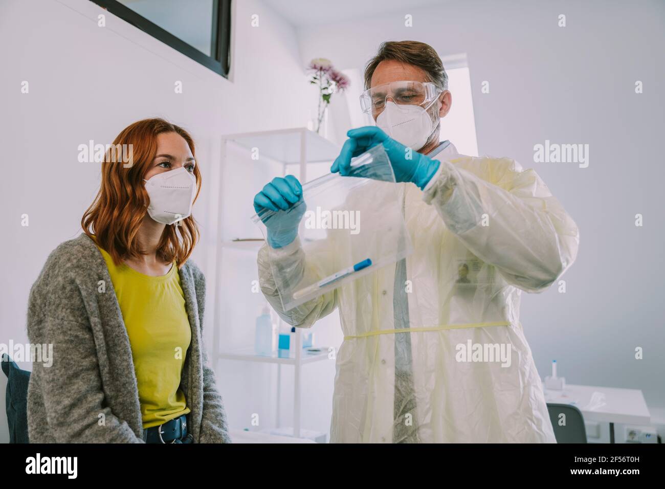 Doctor packaging patient's nasal swab sample in plastic bag while ...