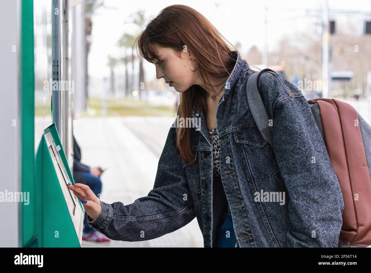 Female commuter using kiosk while standing at tram station Stock Photo ...
