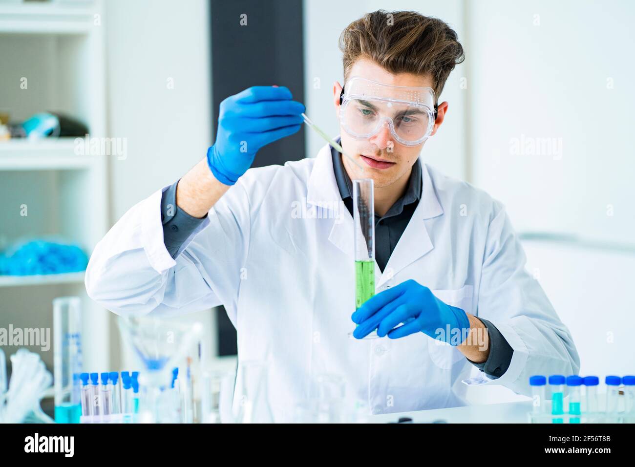 Young scientist mixing chemicals in graduated cylinder at laboratory ...