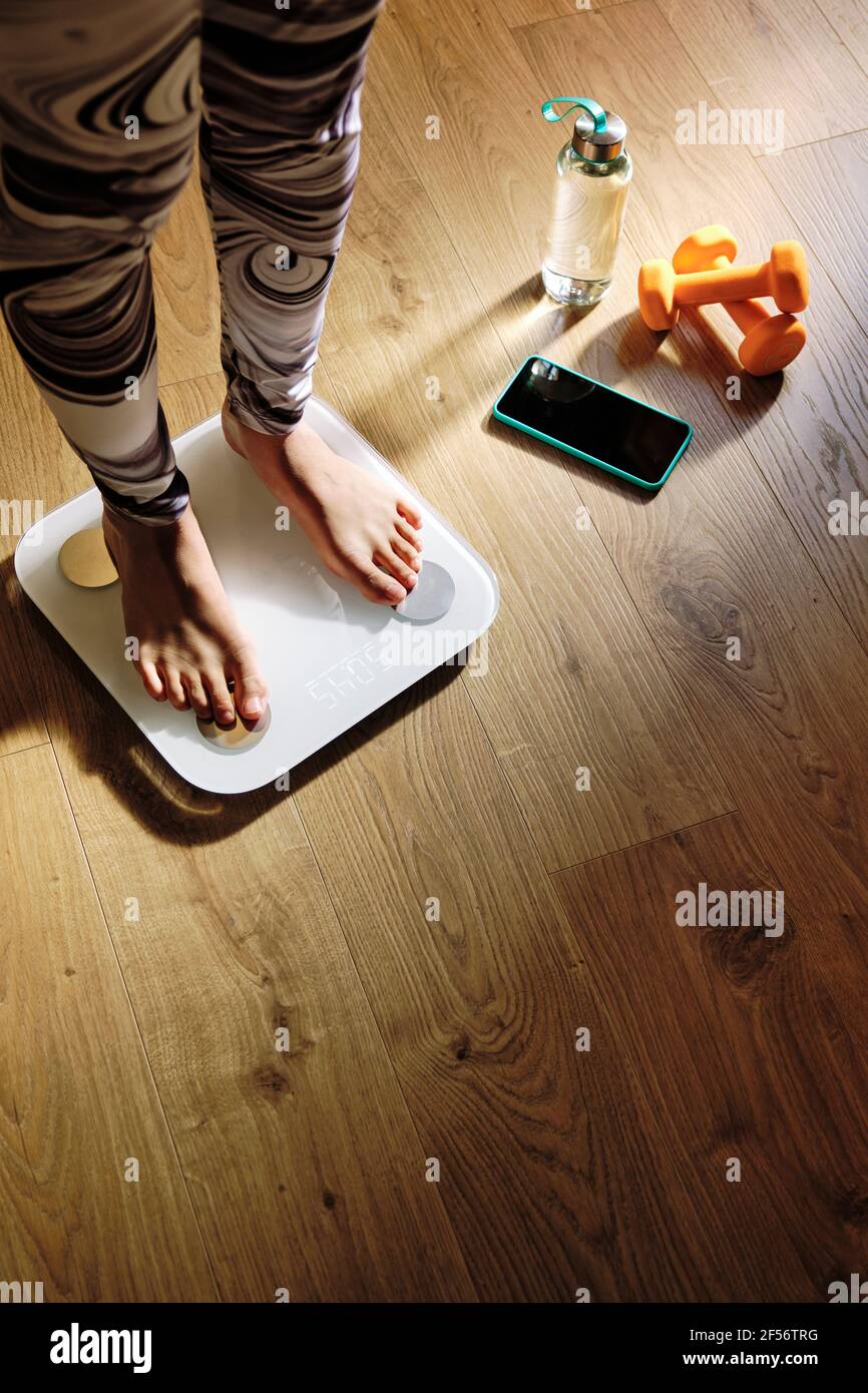 Young woman checking weight on scale at home Stock Photo - Alamy