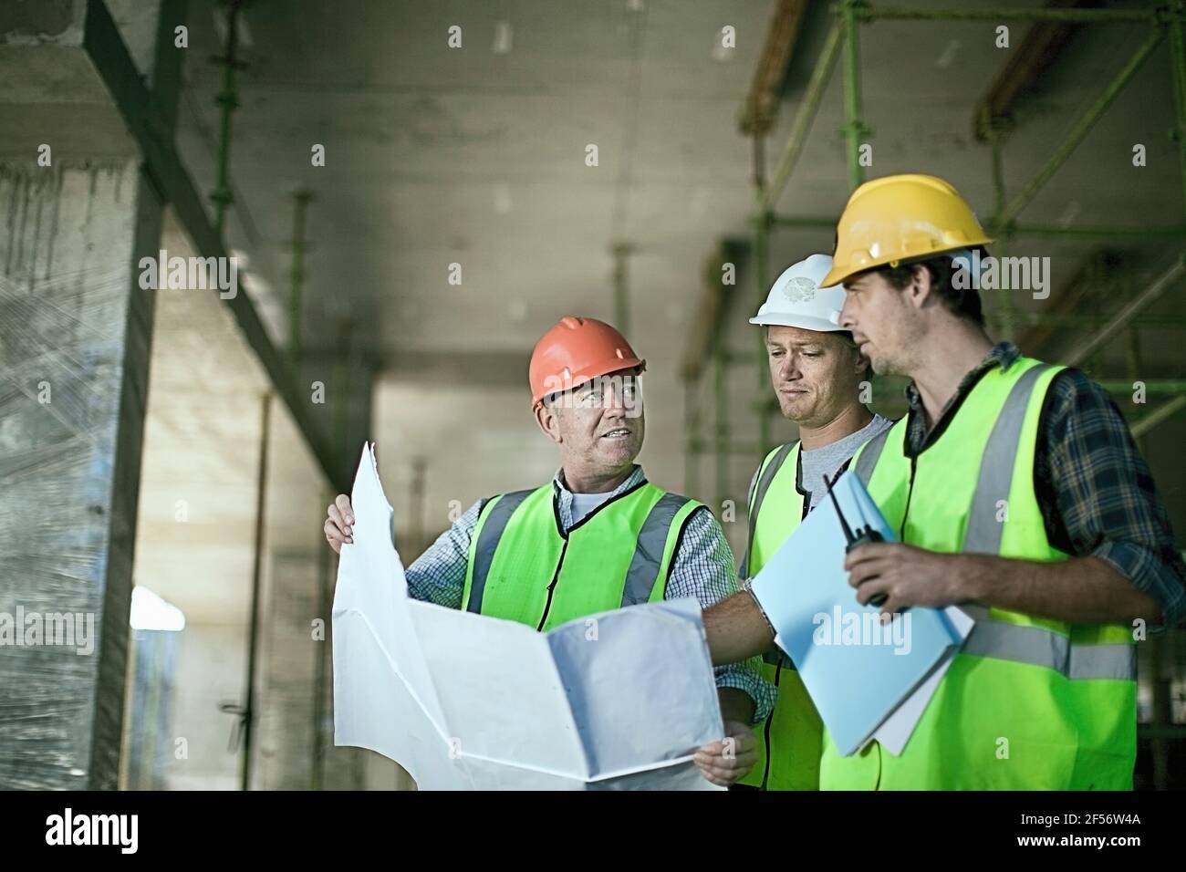 Male construction workers talking over plans at construction site Stock ...