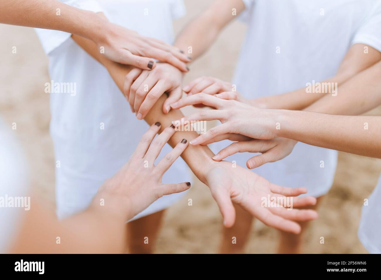 Female friends touching hands on sand Stock Photo - Alamy